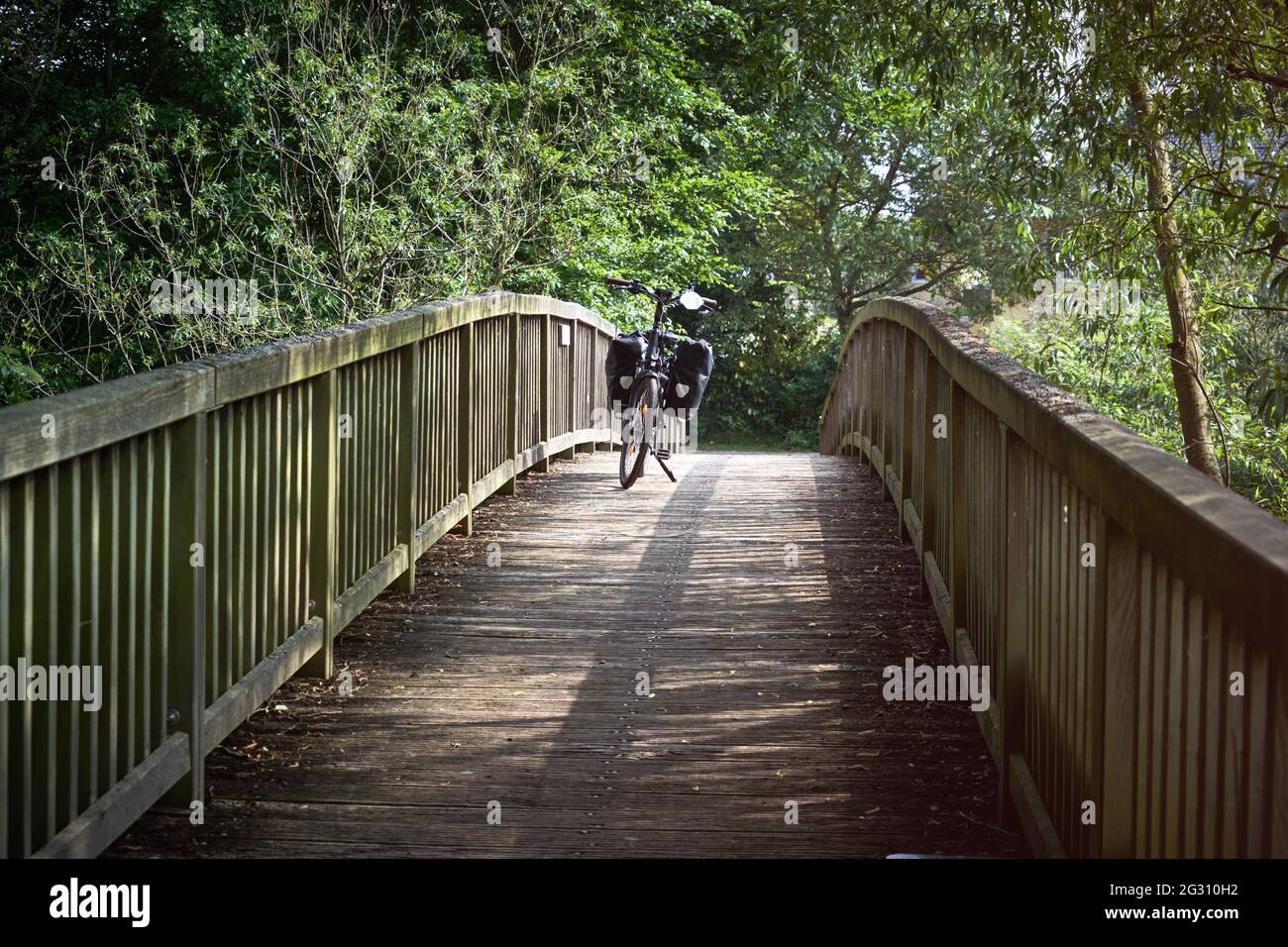 Black bicycle on a bike ride stands on a curved bridge made of wooden ...