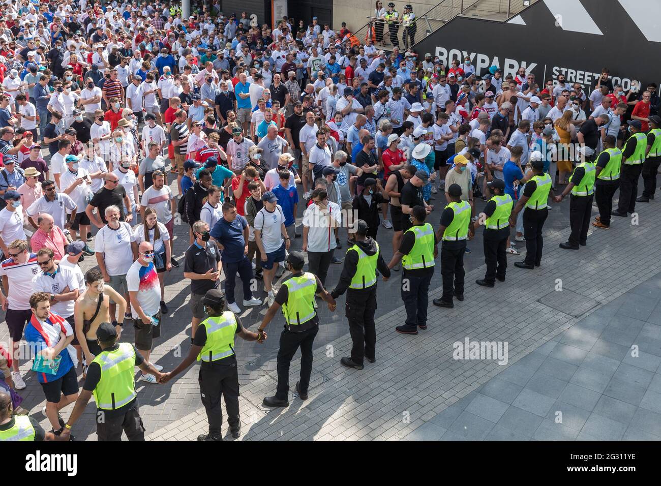 Olympic Way, Wembley Park, UK. 13th June 2021. Stewards form a human ...