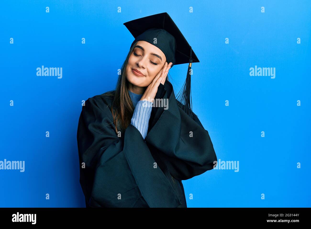 Beautiful brunette young woman wearing graduation cap and ceremony robe ...
