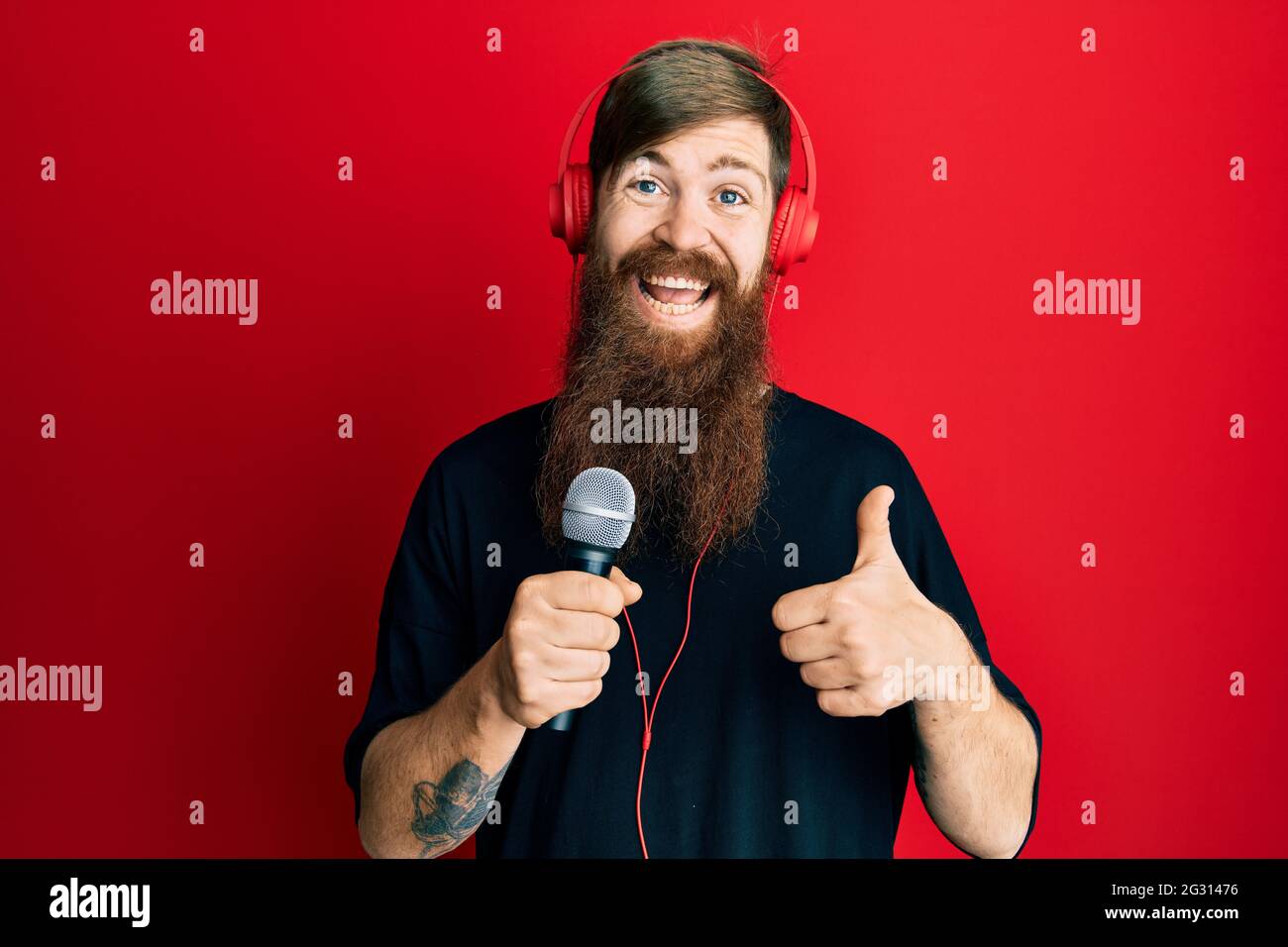 Redhead man with long beard singing song using microphone and wearing ...