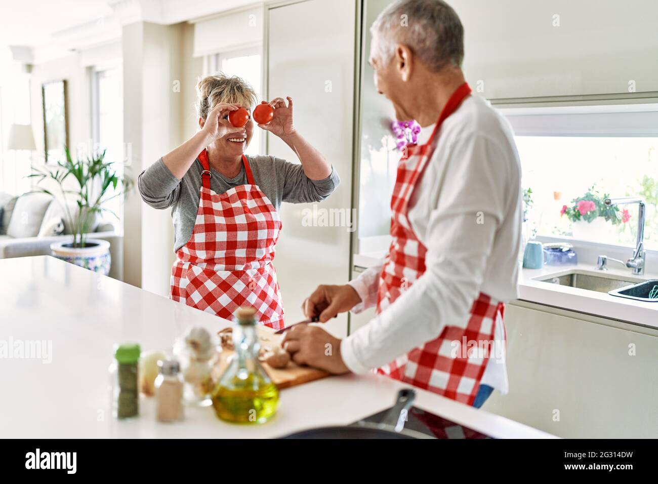 Senior caucasian couple smiling happy cooking at the kitchen. Woman ...