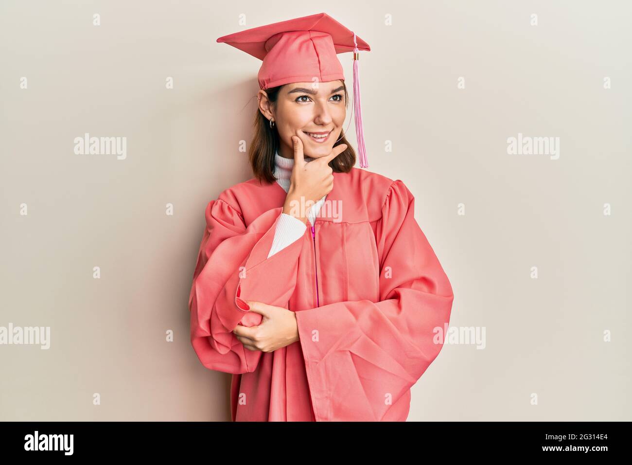 Young caucasian woman wearing graduation cap and ceremony robe with ...