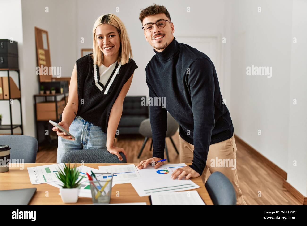 Two business workers smiling happy using smartphone working at the ...