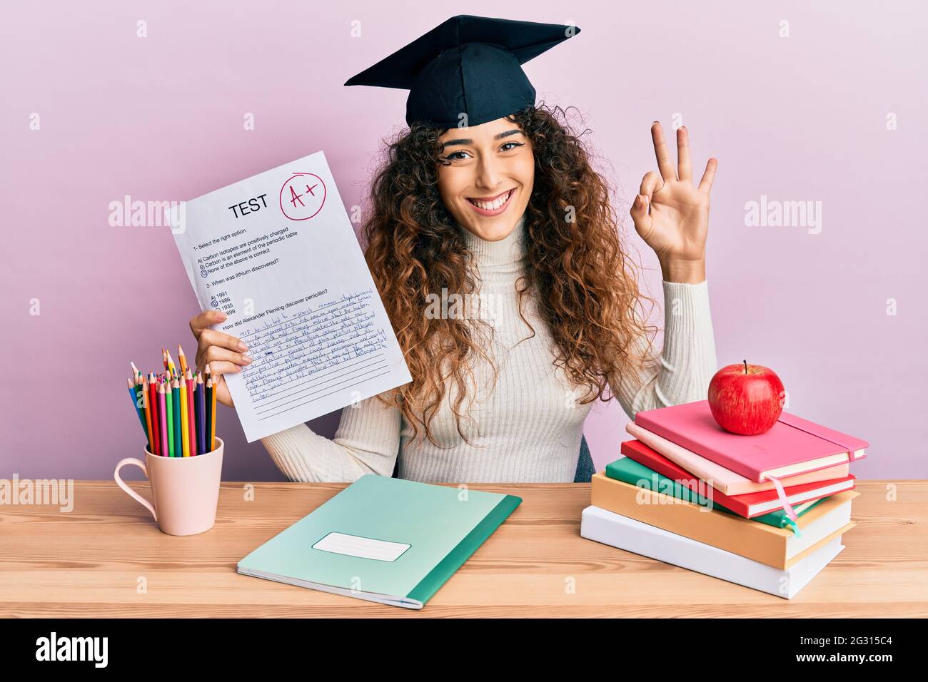 Young hispanic girl wearing graduated hat holding passed test doing ok ...