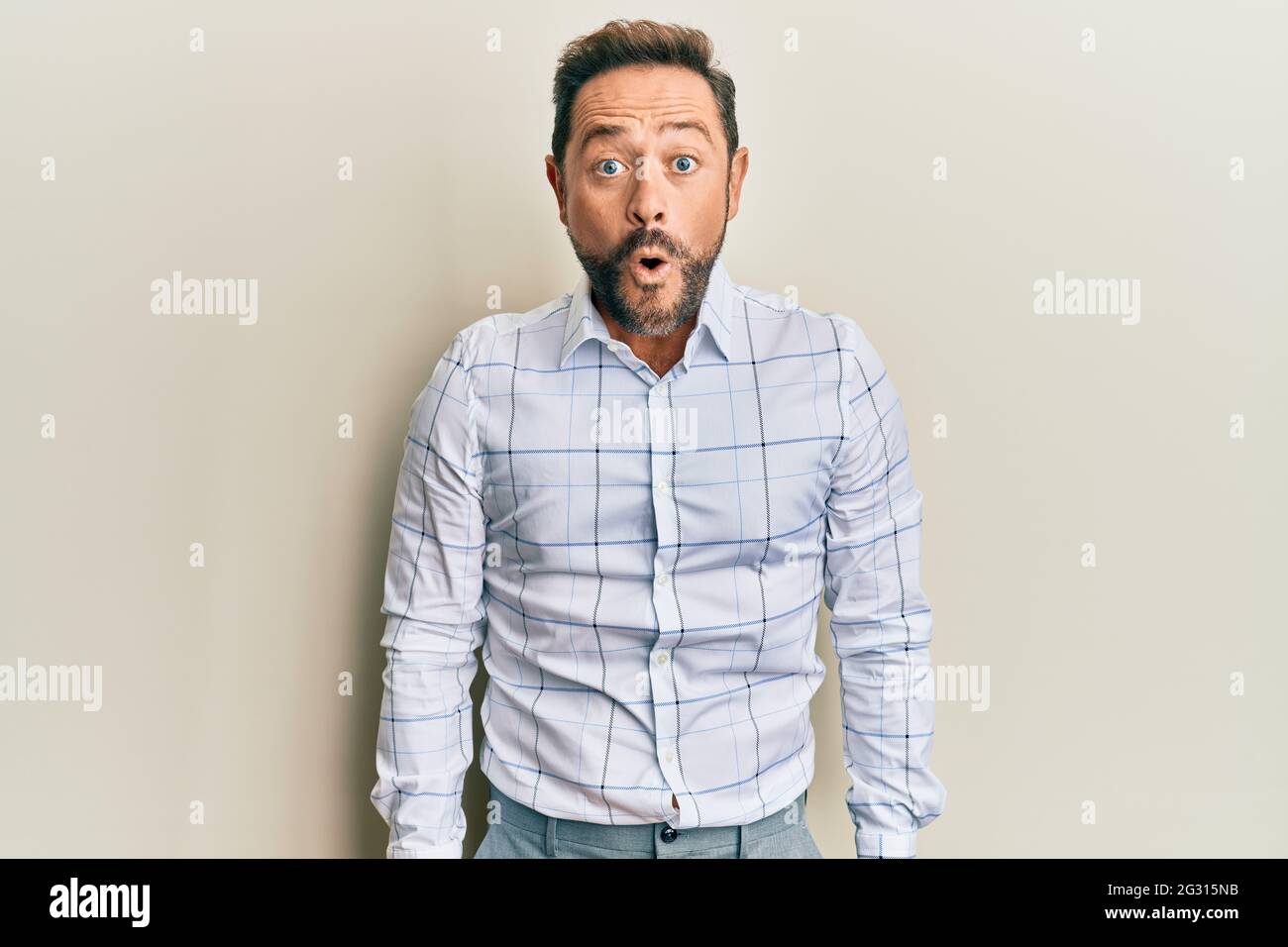 Middle age man wearing business clothes scared and amazed with open ...