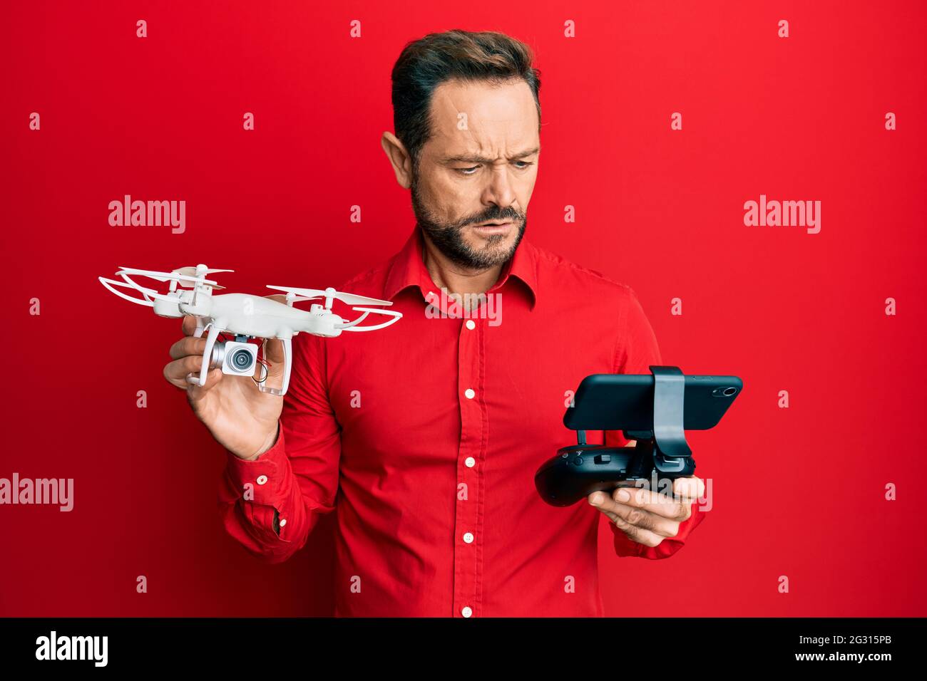 Middle age man using drone in shock face, looking skeptical and ...