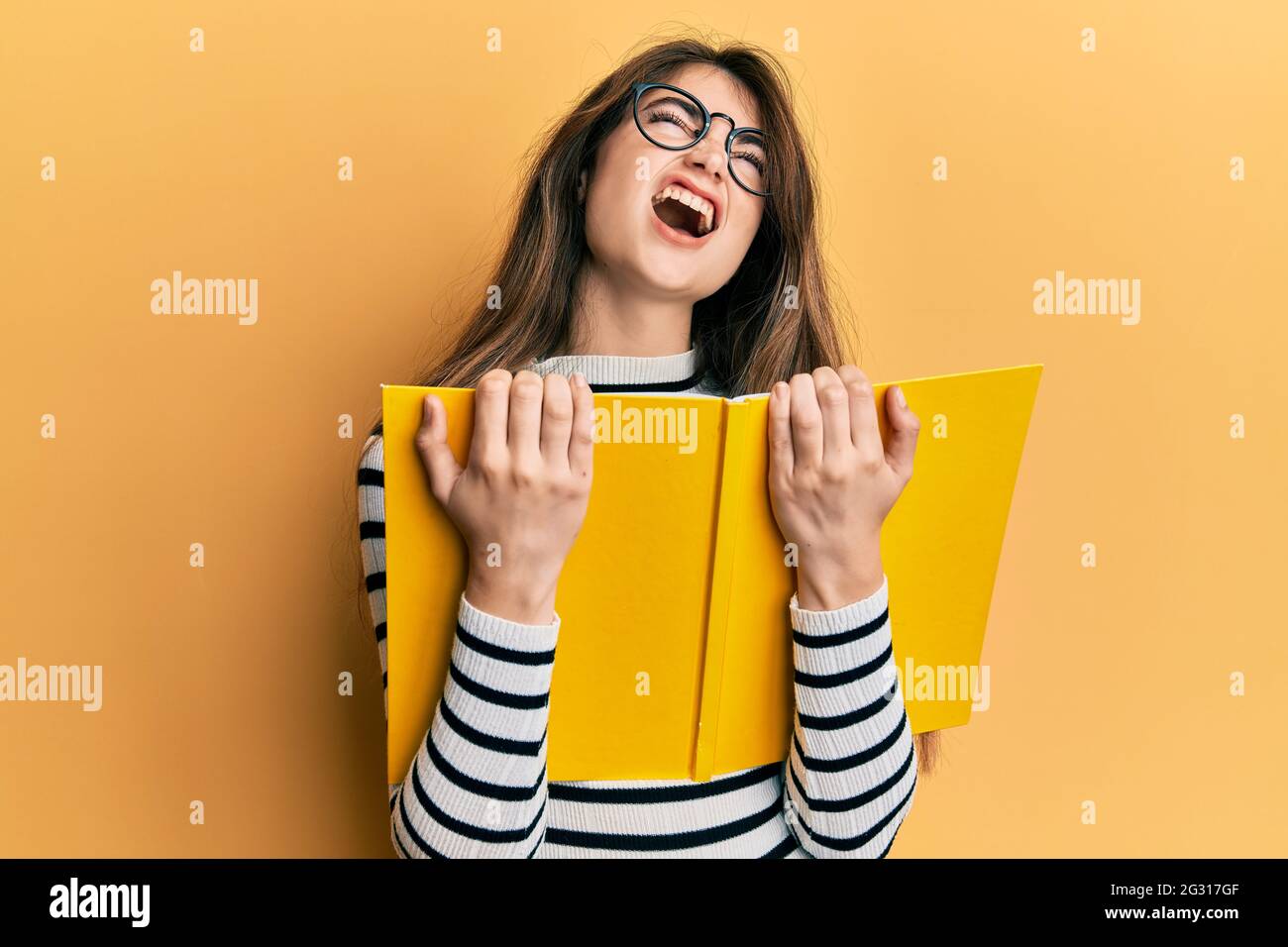 Young caucasian woman reading a book wearing glasses angry and mad ...