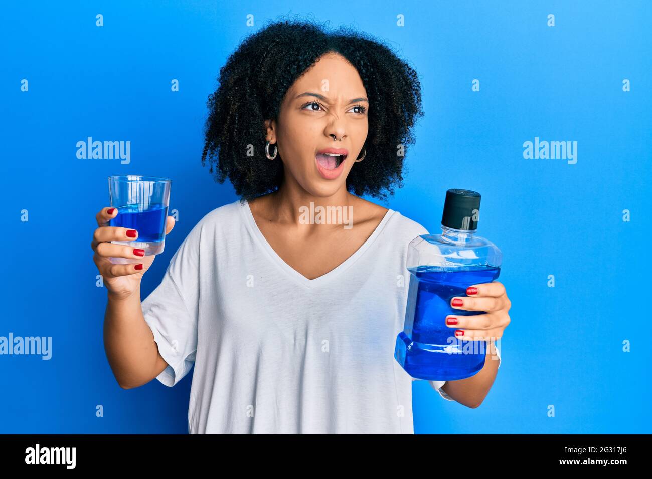 Young african american girl holding mouthwash for fresh breath angry ...