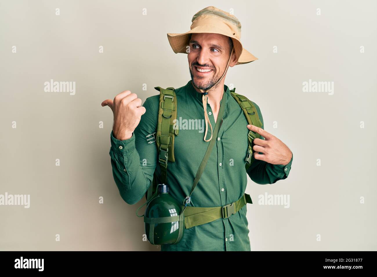 Handsome man with beard wearing explorer hat and backpack smiling with ...