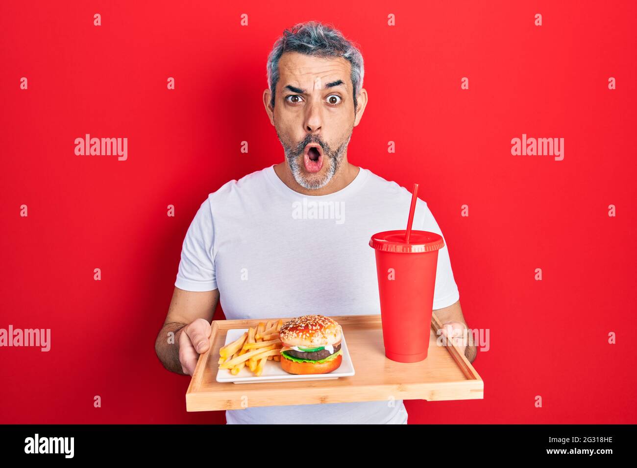 Handsome middle age man with grey hair eating a tasty classic burger ...