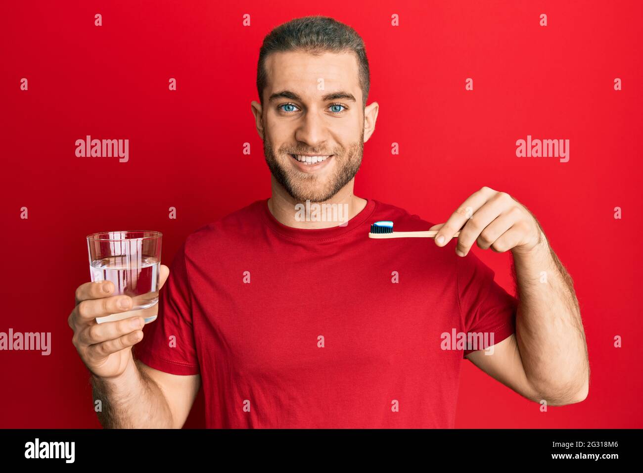 Young caucasian man holding toothbrush with toothpaste smiling with a ...