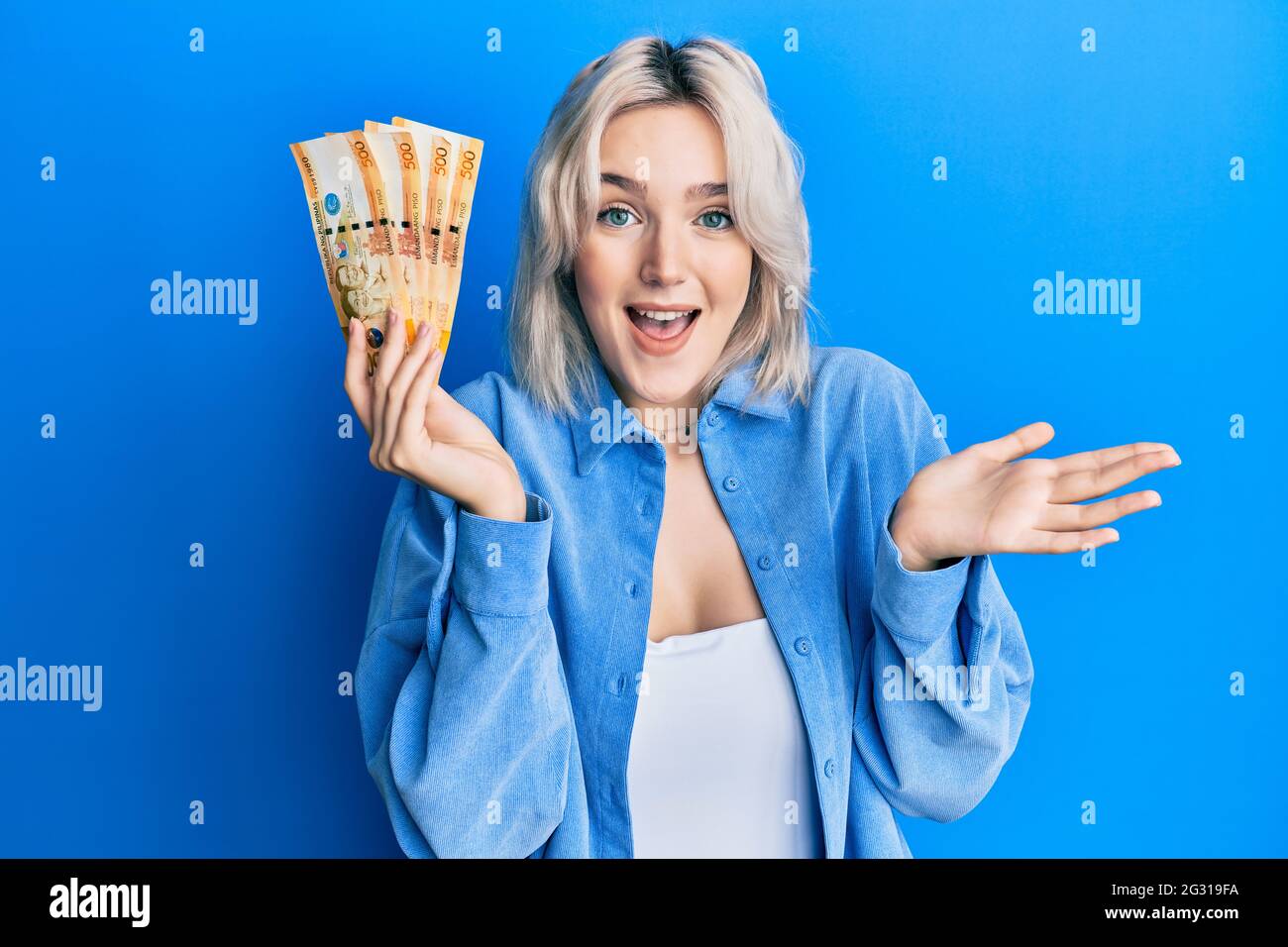 Young blonde girl holding philippine peso banknotes celebrating ...
