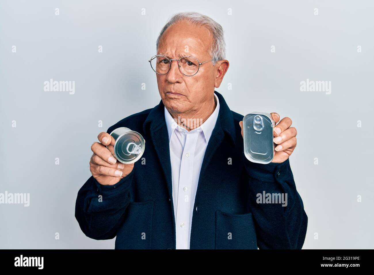 Senior man with grey hair holding canned food clueless and confused ...