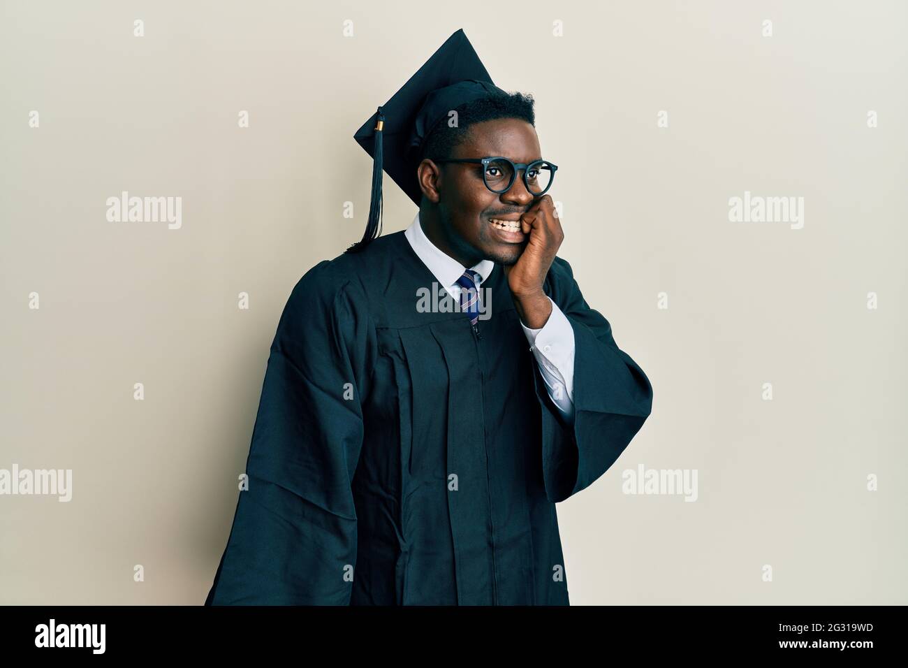 Handsome black man wearing graduation cap and ceremony robe looking ...