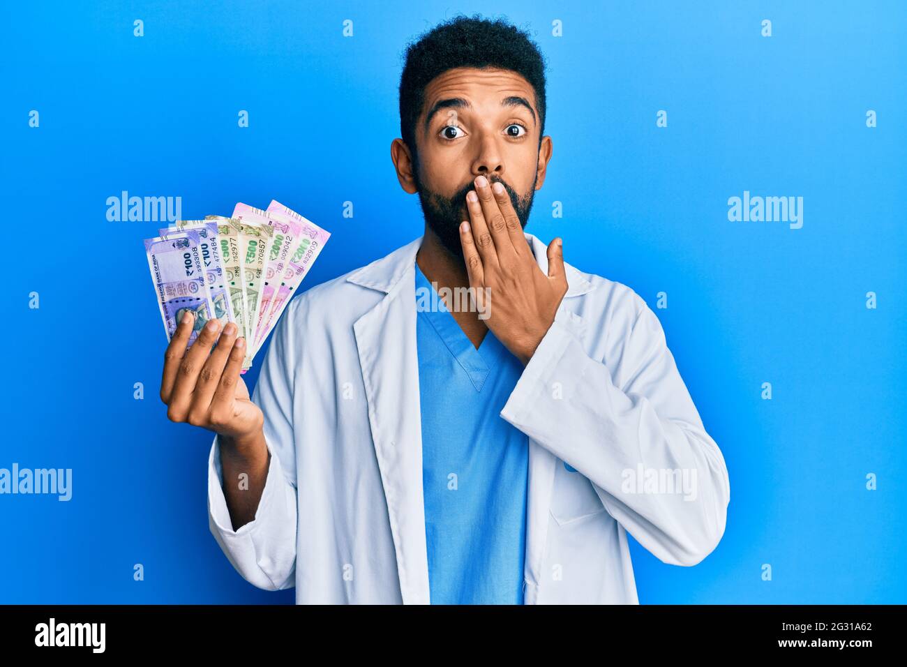 Handsome hispanic man with beard wearing medical uniform holding indian ...