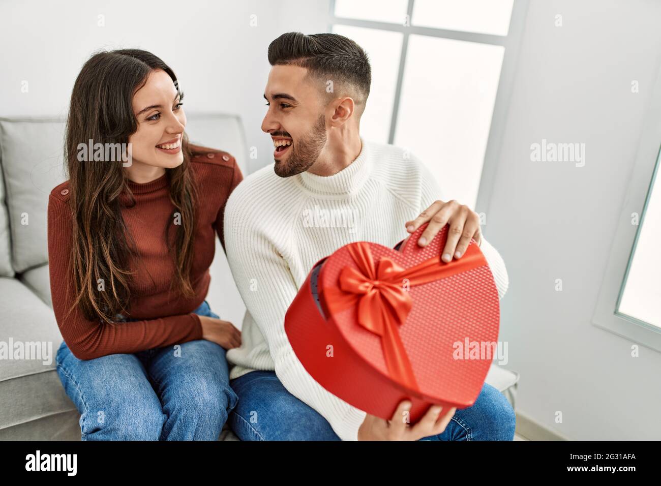 Young hispanic couple smiling happy surprising with valentine gift at ...