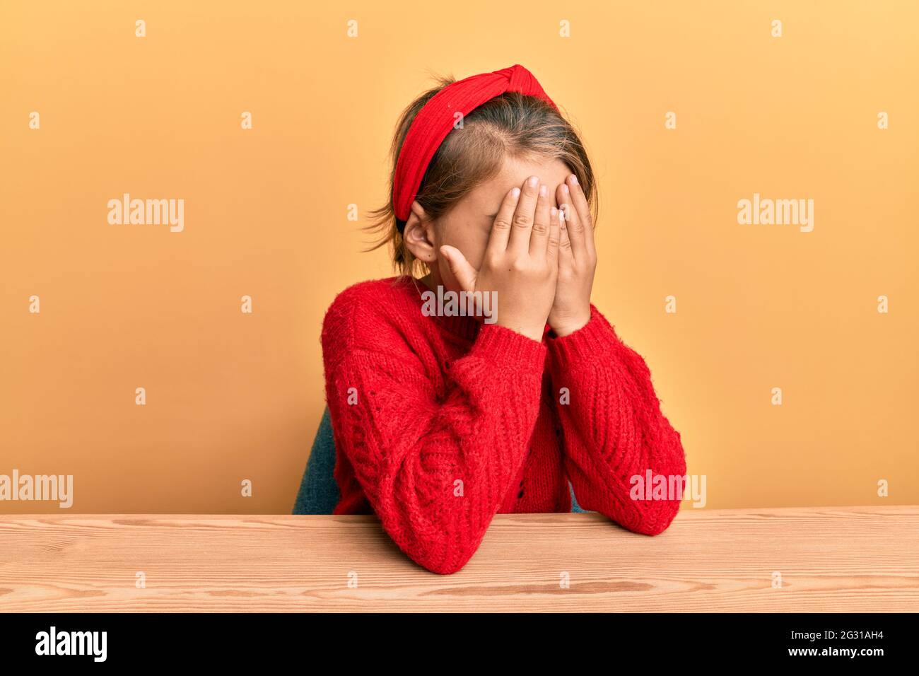 Little beautiful girl wearing casual clothes sitting on the table with ...