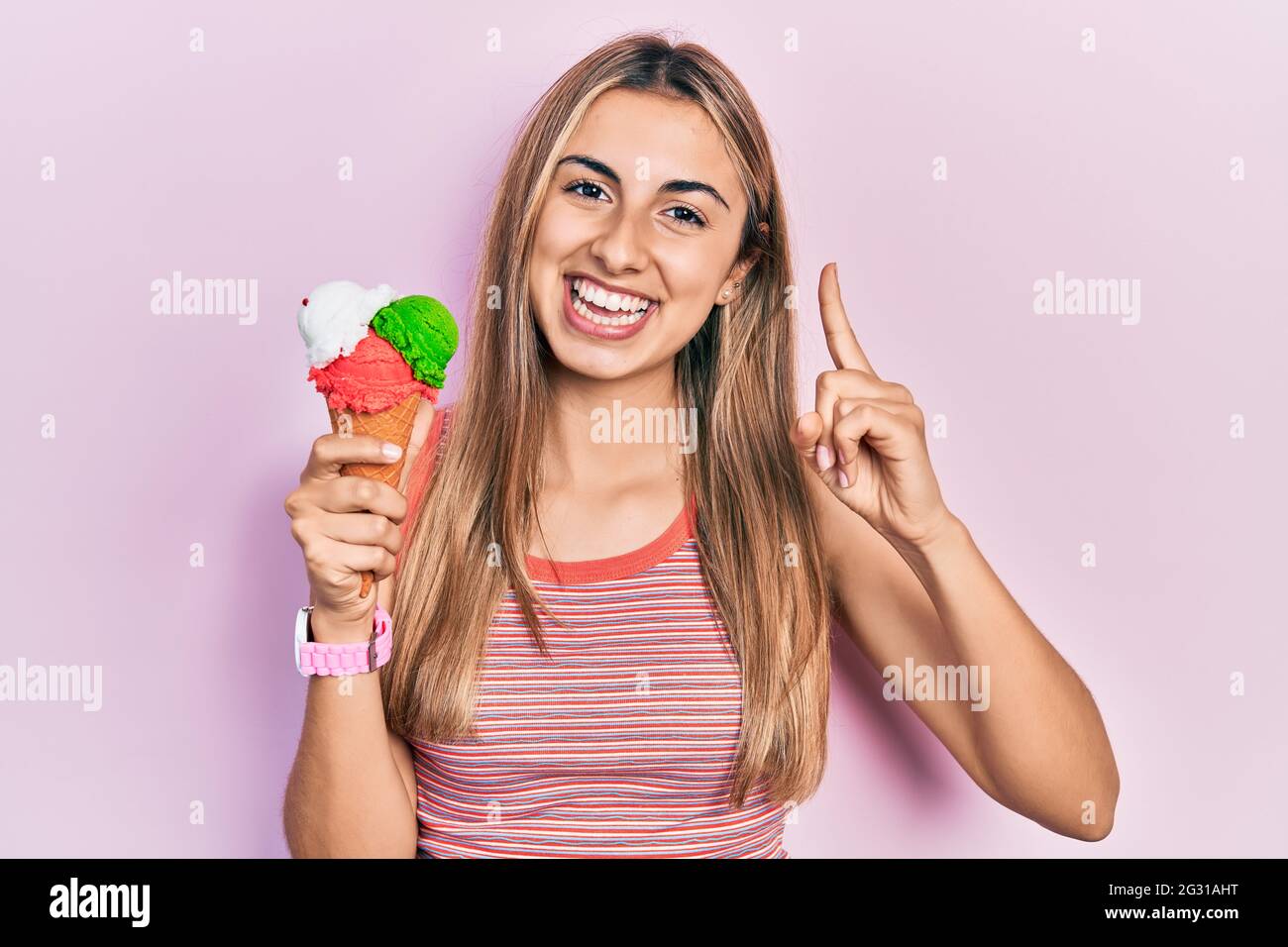 Beautiful hispanic woman holding ice cream smiling with an idea or ...