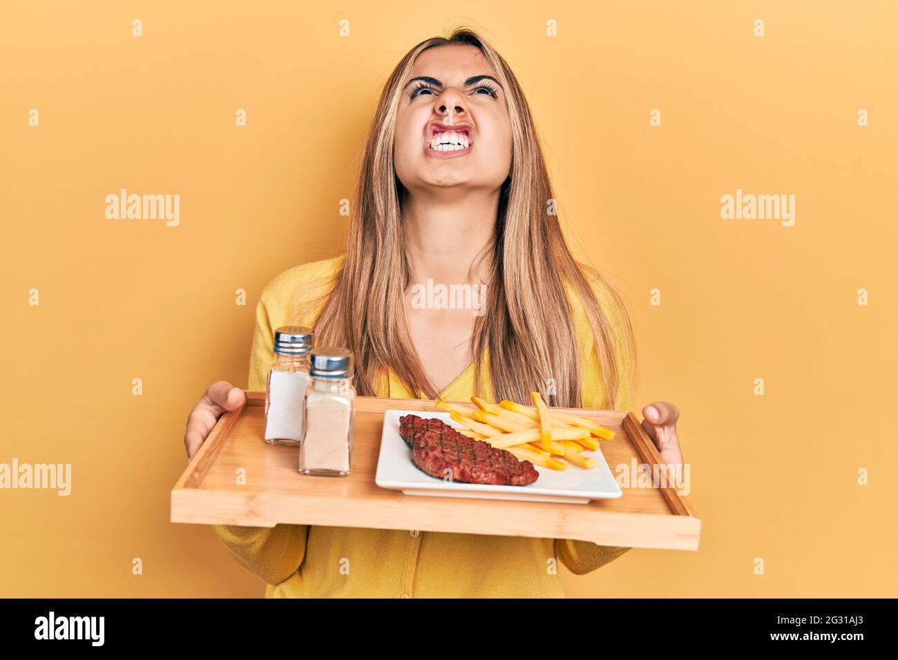 Beautiful hispanic woman holding tray with lunch angry and mad ...