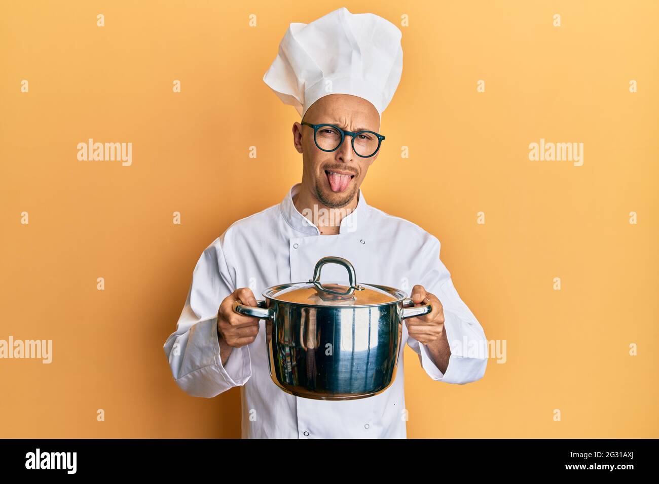 Bald man with beard wearing professional cook holding cooking pot ...