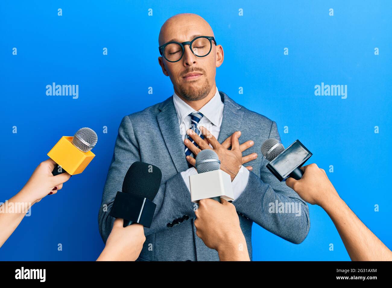 Bald man with beard being interviewed by reporters holding microphones ...