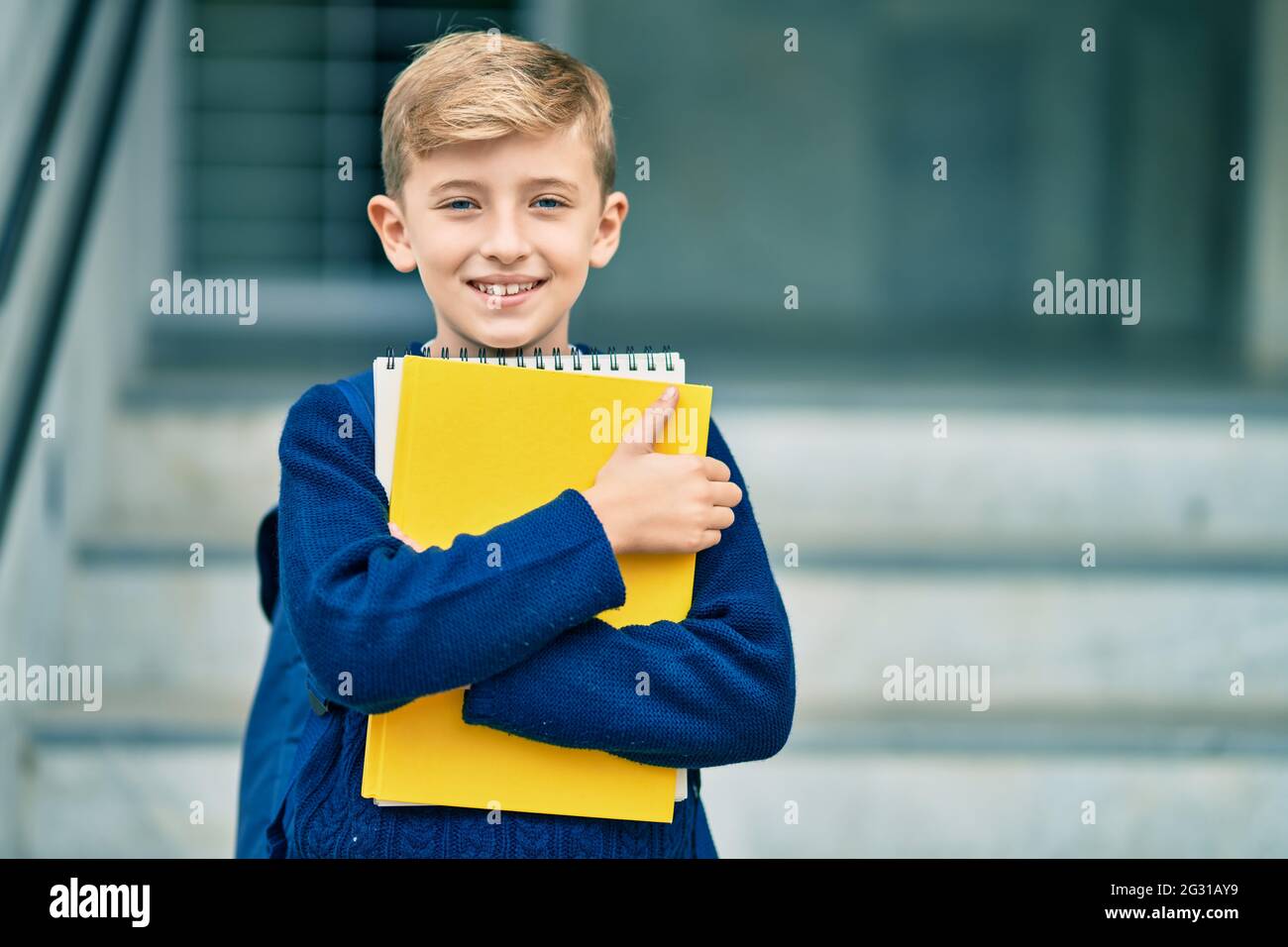 Adorable blond student kid smiling happy holding book at the school ...