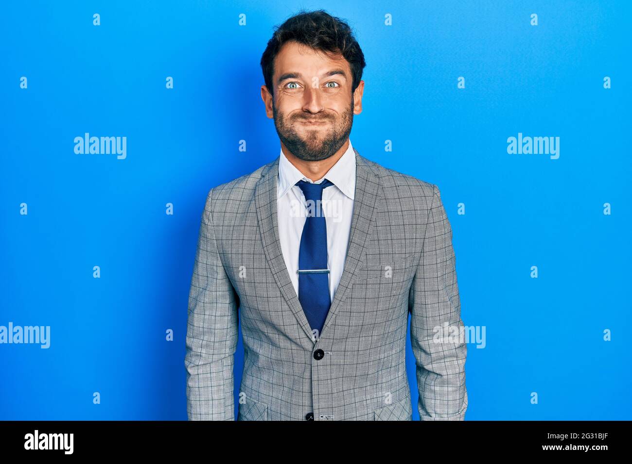 Handsome man with beard wearing business suit and tie puffing cheeks ...