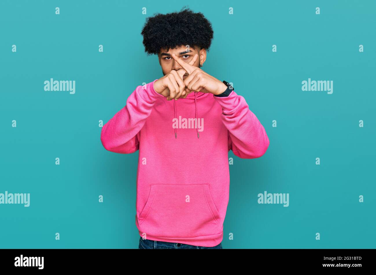 Young african american man with afro hair wearing casual pink sweatshirt rejection expression ...