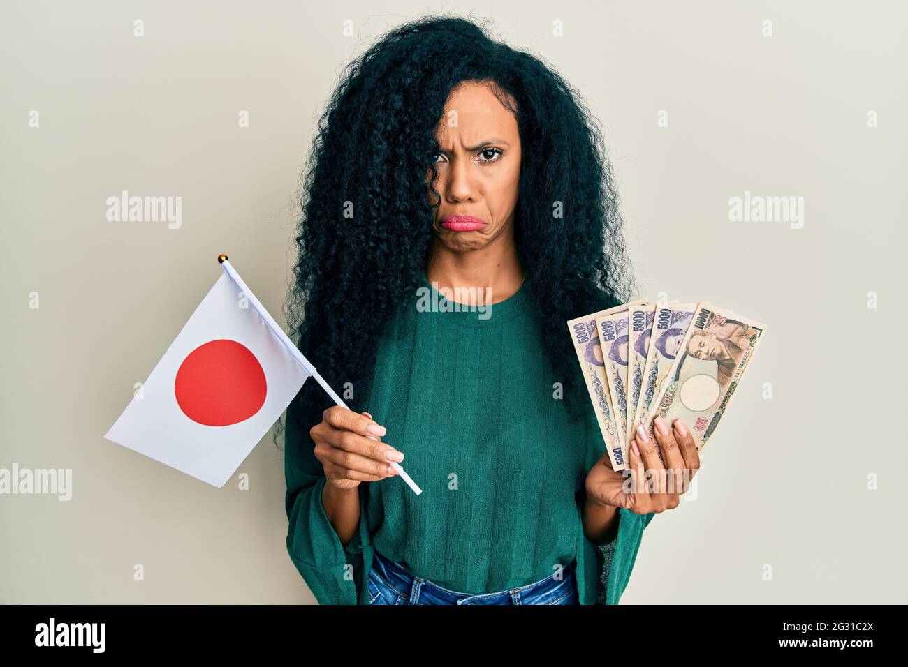Middle age african american woman holding japan flag and yen banknotes ...