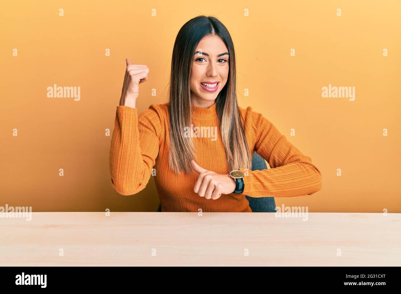 Young hispanic woman wearing casual clothes sitting on the table ...
