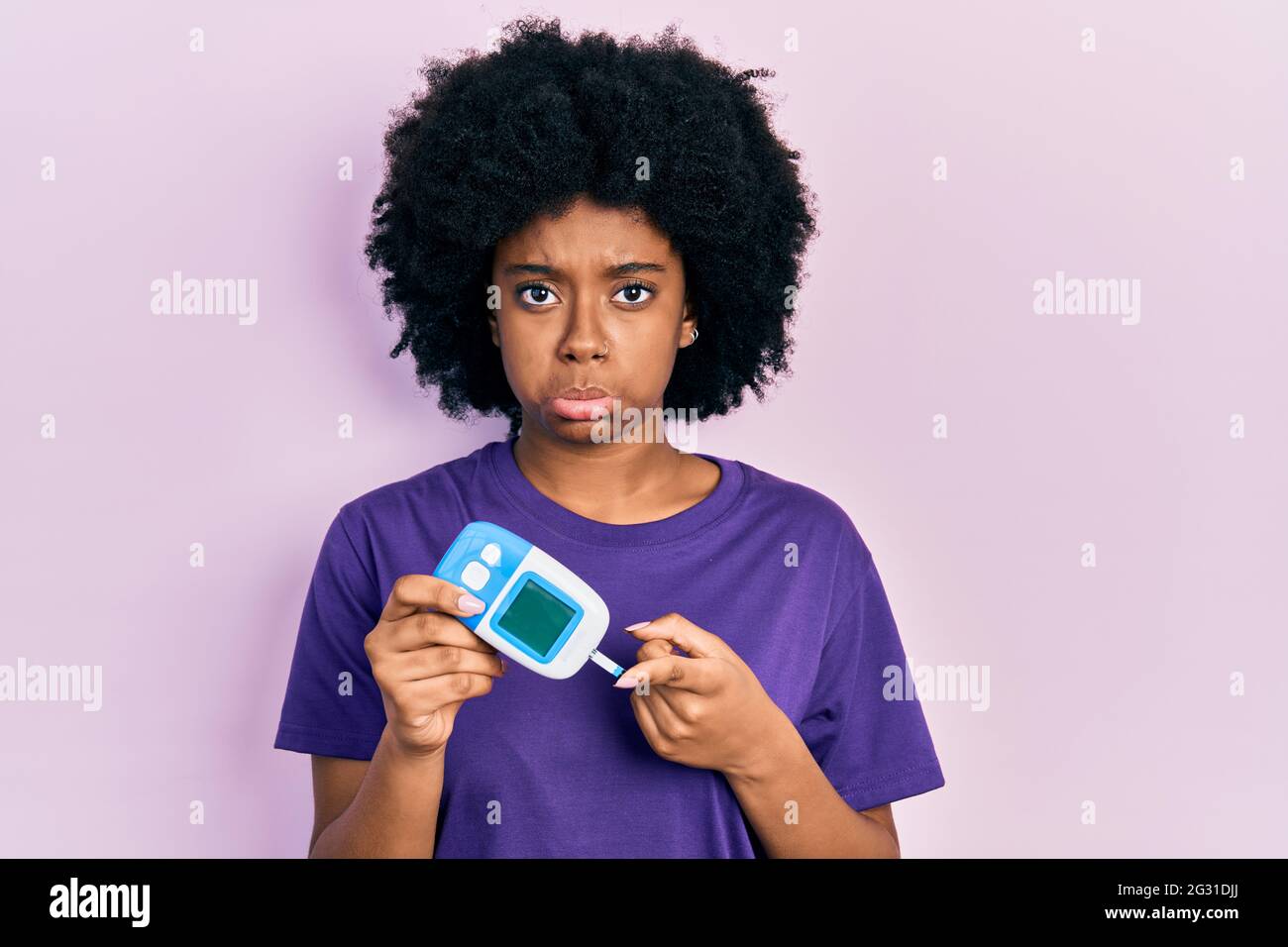 Young african american woman holding glucometer device depressed and ...