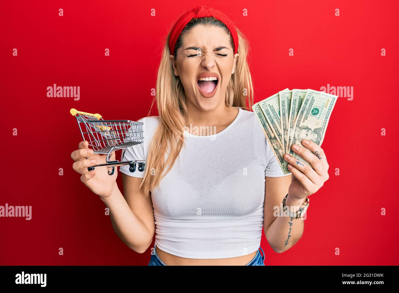 Young caucasian woman holding small supermarket shopping cart and ...