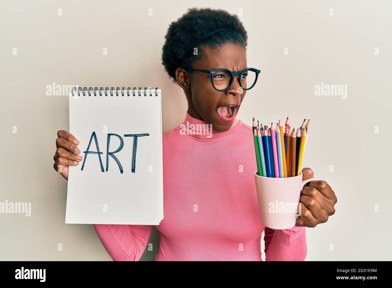 Young african american girl holding art notebook and colored pencils ...