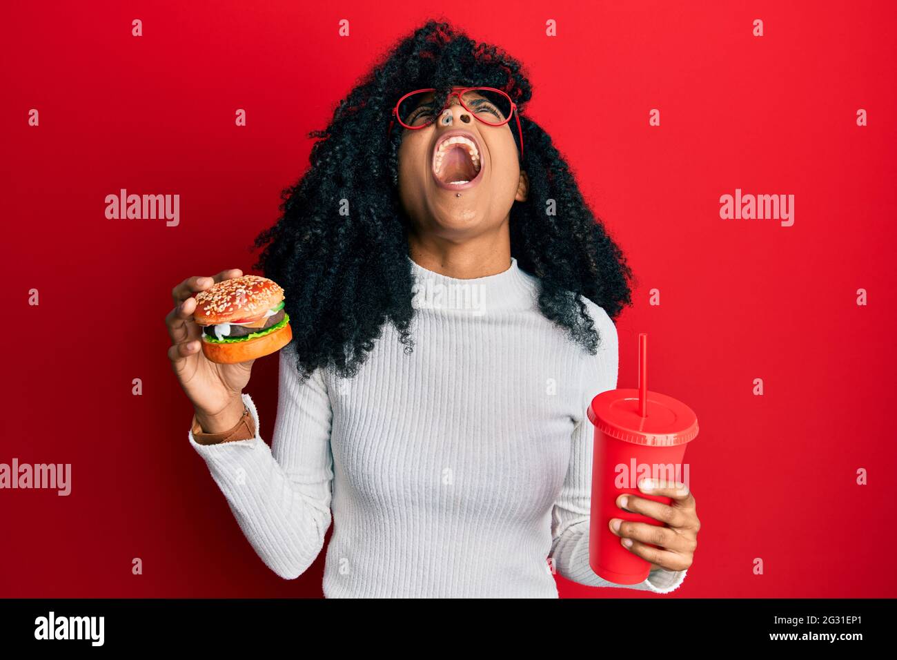 African american woman with afro hair eating a tasty classic burger and ...