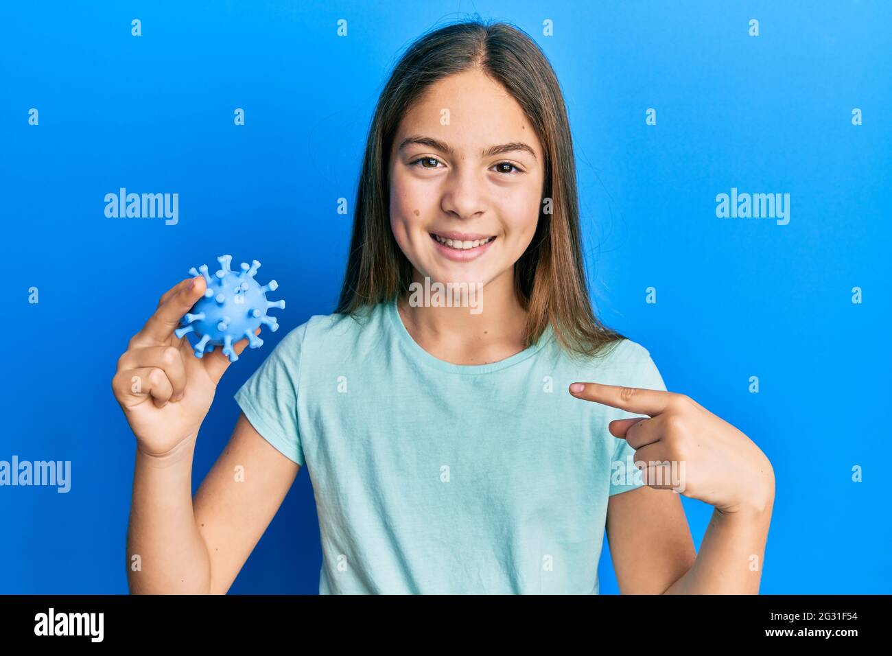 Beautiful brunette little girl holding virus toy pointing finger to one ...