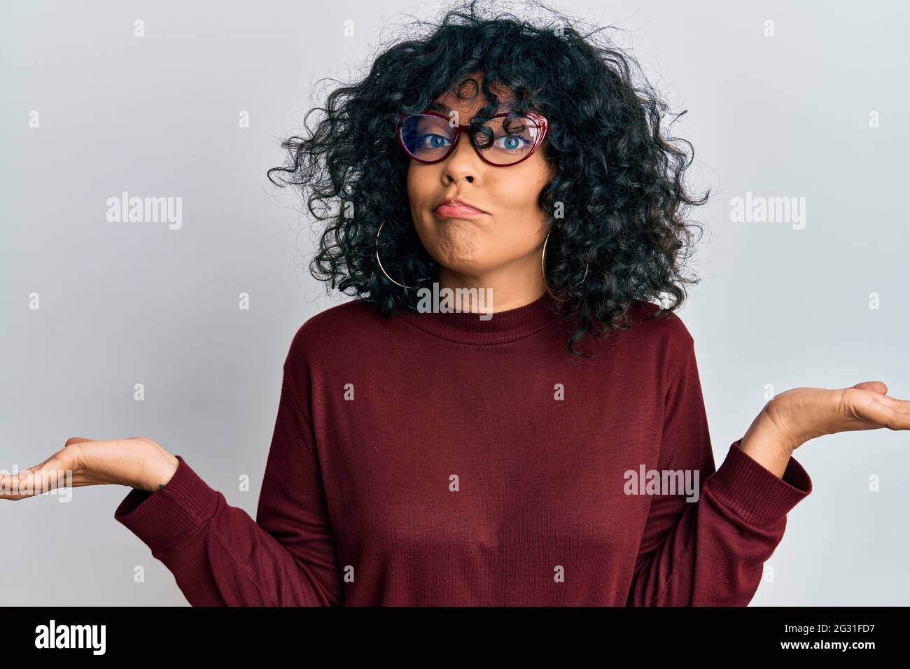 Young hispanic woman wearing casual clothes and glasses clueless and ...