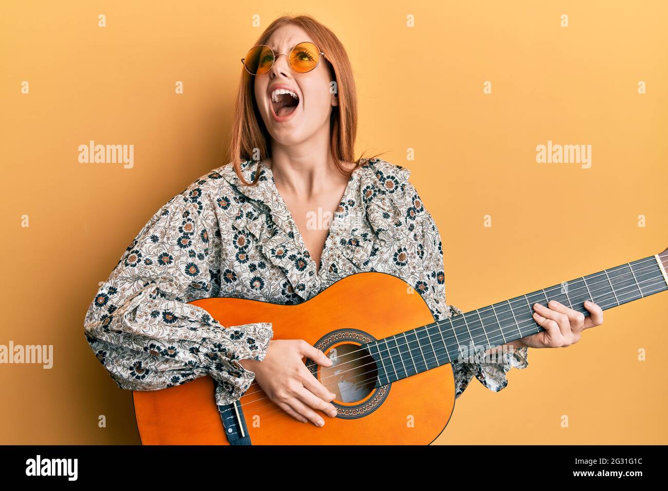 Young irish woman wearing boho style playing classical guitar angry and ...