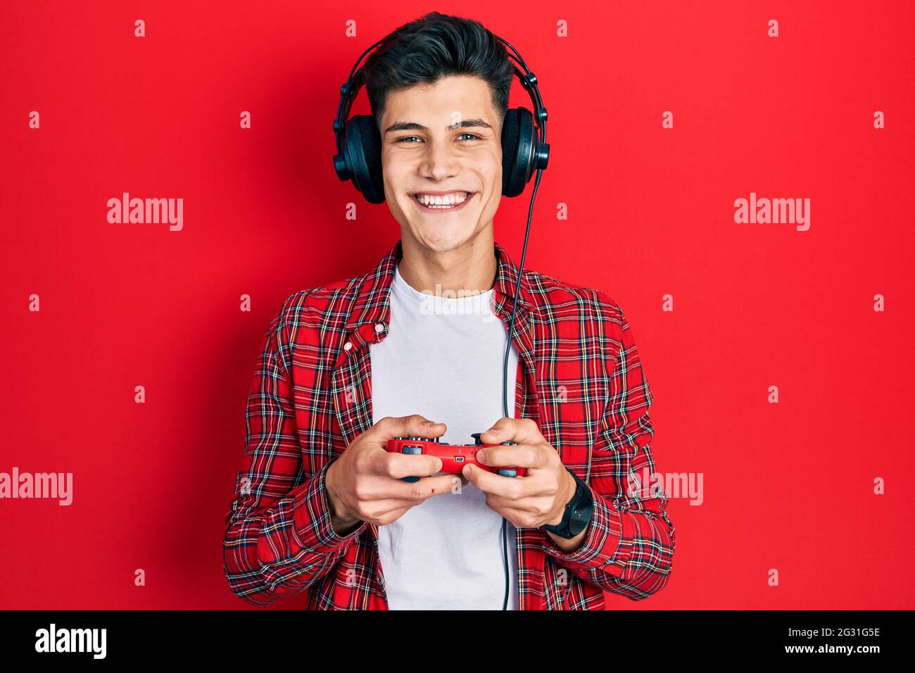 Young hispanic man playing video game holding controller smiling with a ...