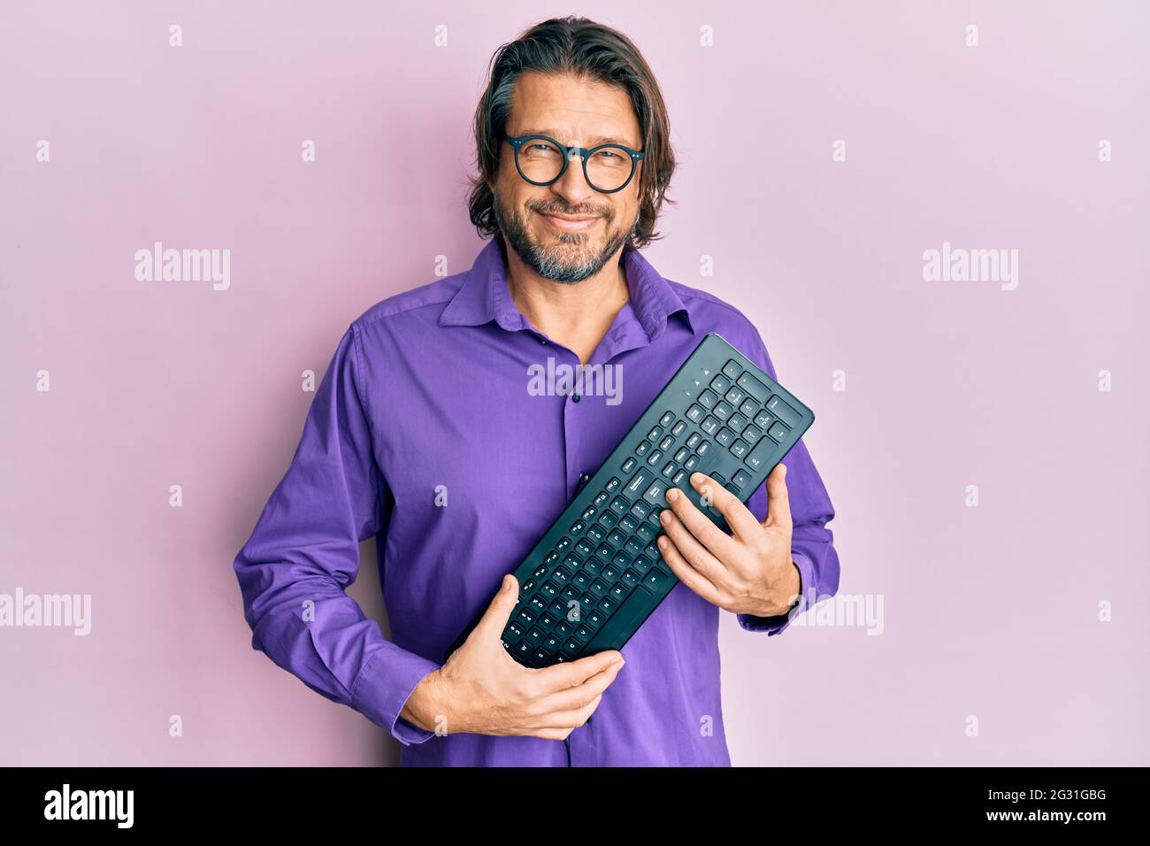 Middle age handsome man holding computer keyboard looking positive and ...