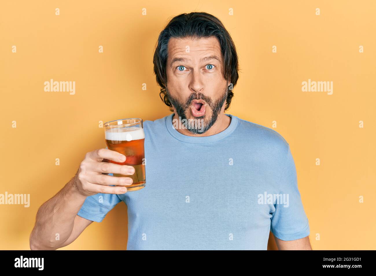 Middle age caucasian man drinking a pint of beer scared and amazed with ...