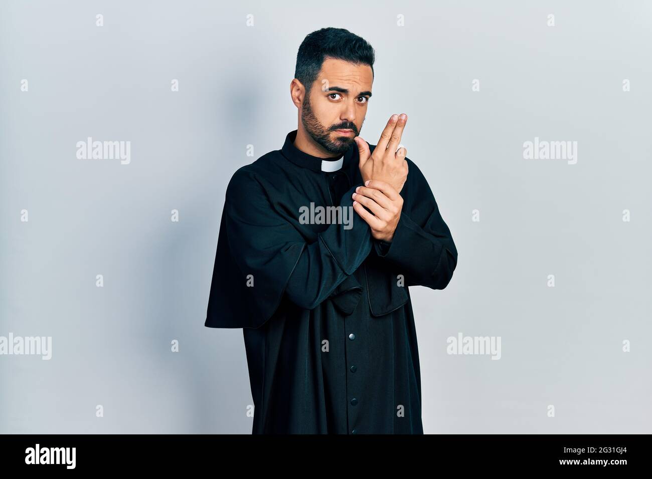 Handsome hispanic man with beard wearing catholic priest robe holding ...