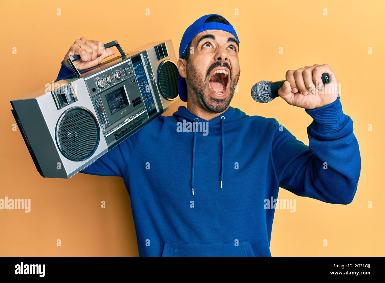 Young hispanic man holding boombox, listening to music singing with ...