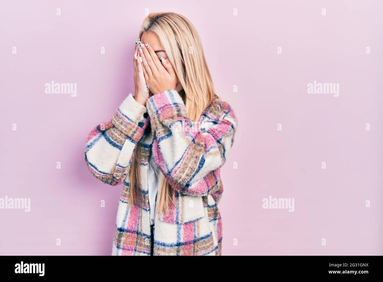 Young blonde girl wearing casual clothes with sad expression covering ...