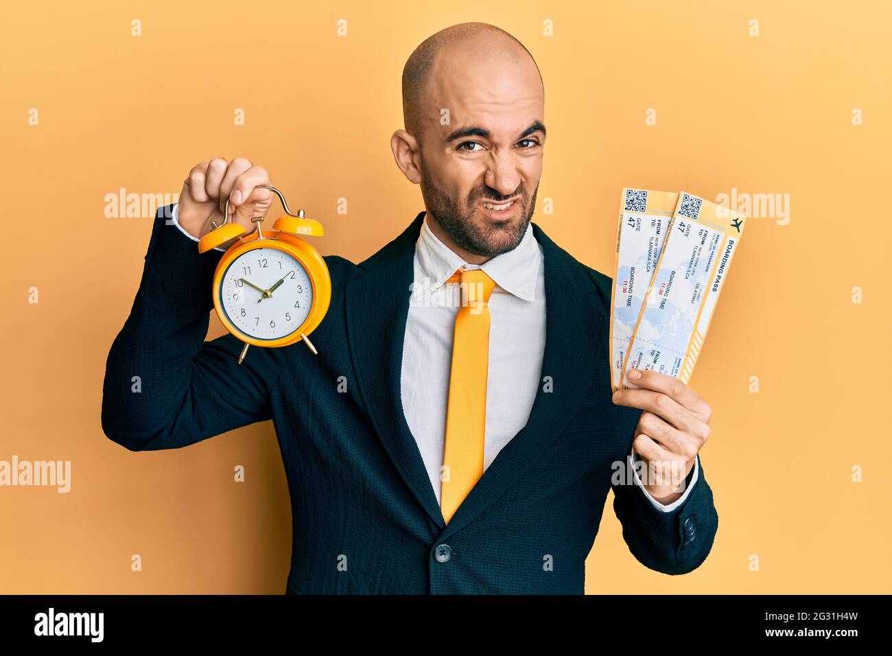 Young hispanic business man holding boarding pass and alarm clock ...