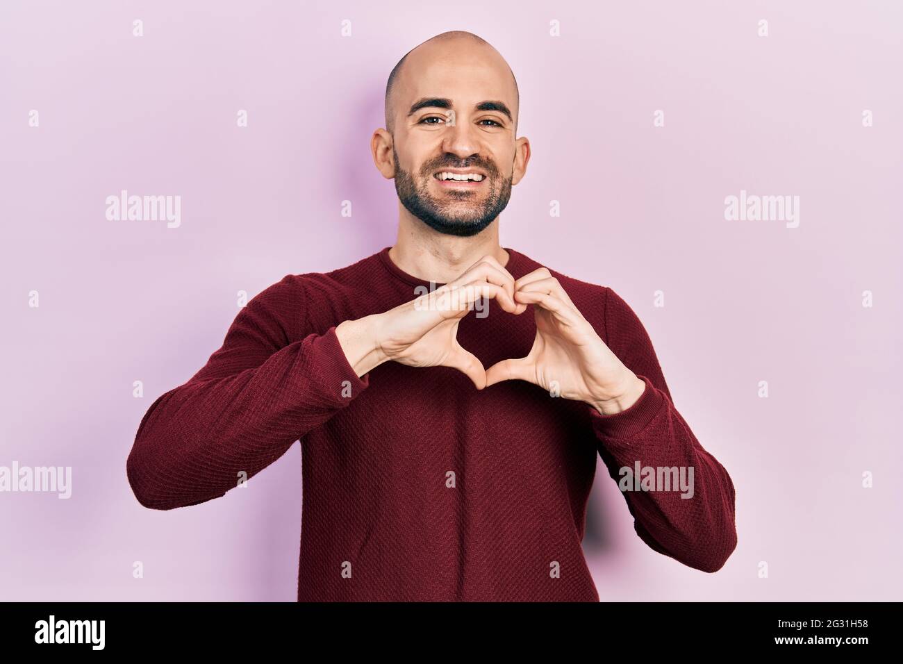 Young bald man wearing casual clothes smiling in love doing heart ...
