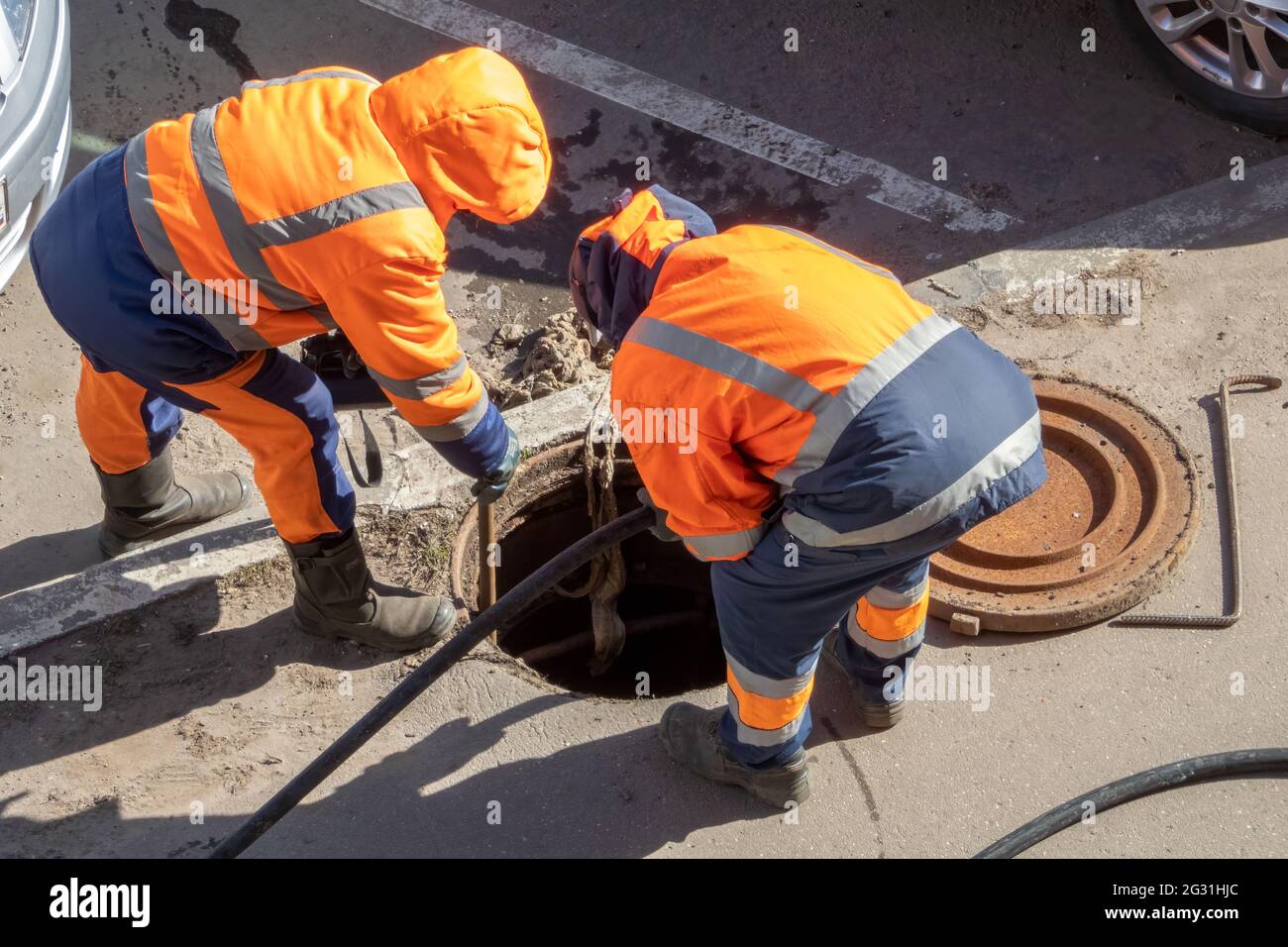 Workers over the open sewer hatch repairing water supply system Stock ...