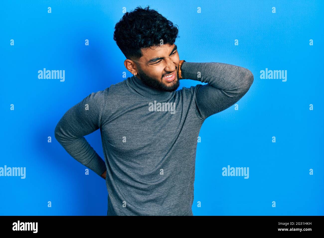 Arab man with beard wearing turtleneck sweater suffering of neck ache ...