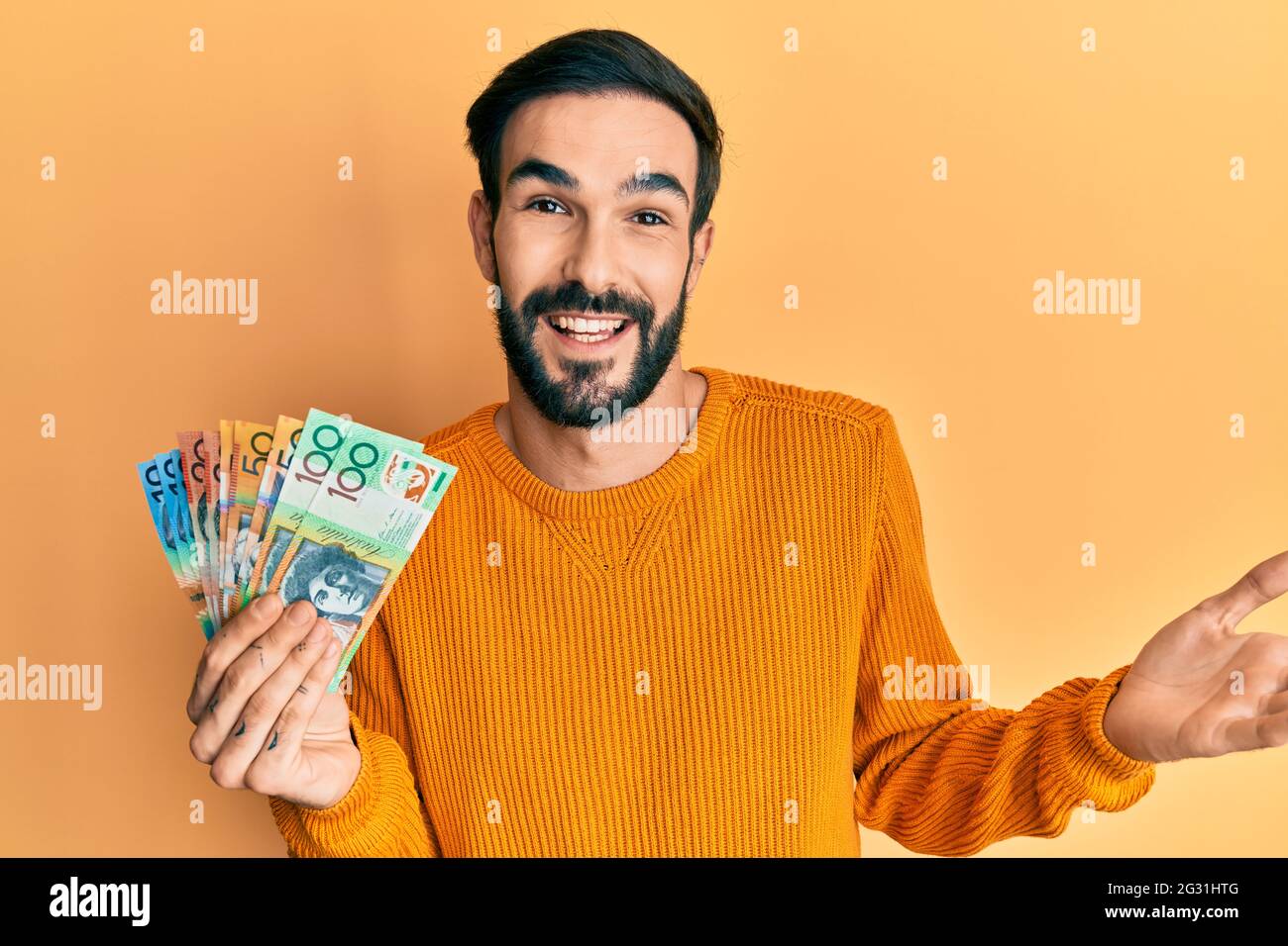 Young hispanic man holding australian dollars celebrating achievement ...