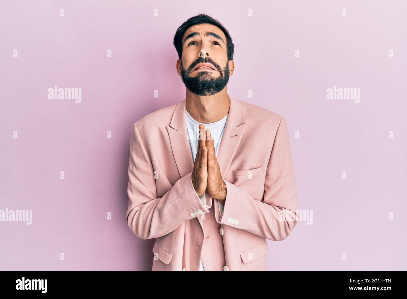 Young hispanic man wearing business jacket begging and praying with ...