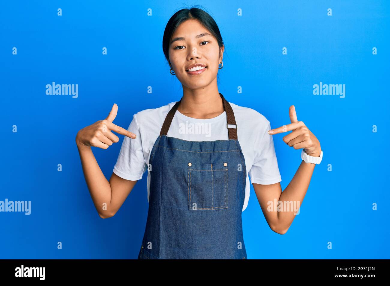 Young chinese woman wearing waiter apron looking confident with smile ...